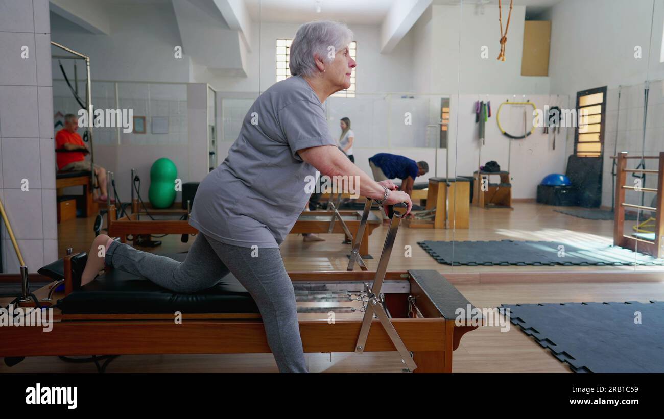 Older woman using Pilates Machine to stretch body. Elderly person ...