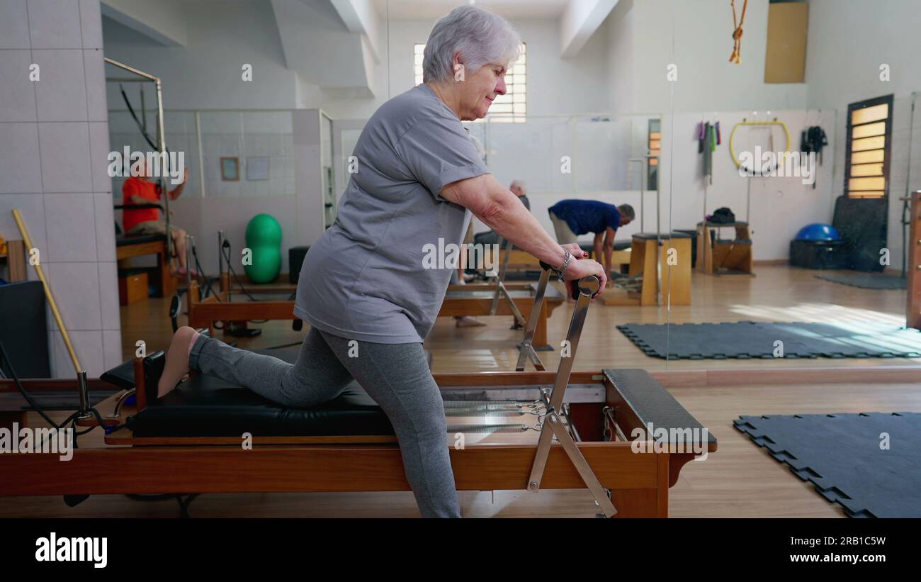 Older woman using Pilates Machine to stretch body. Elderly person ...