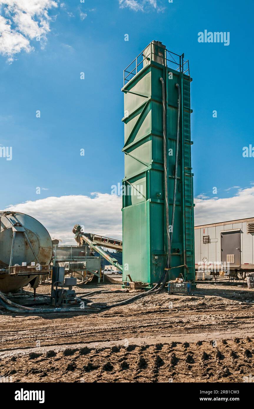 A boxy green tower stands in a flattened area in an active landfill ...