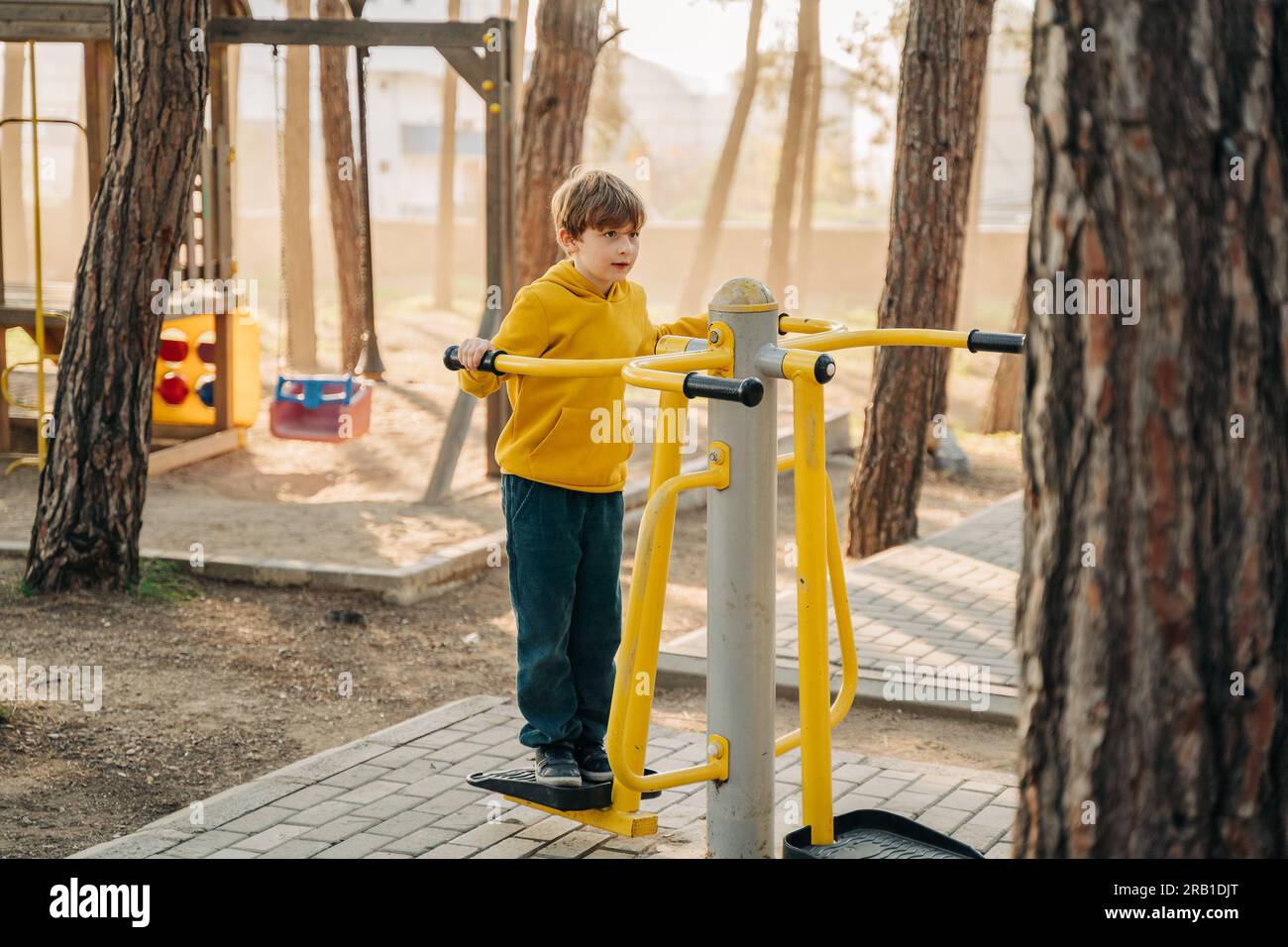 Elementary school boy using fitness exercise equipment in the public ...
