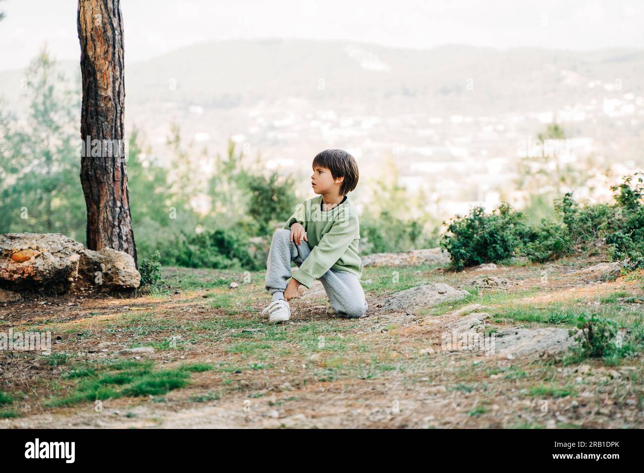 School boy kid relaxing sitting on the ground taking a breather during ...