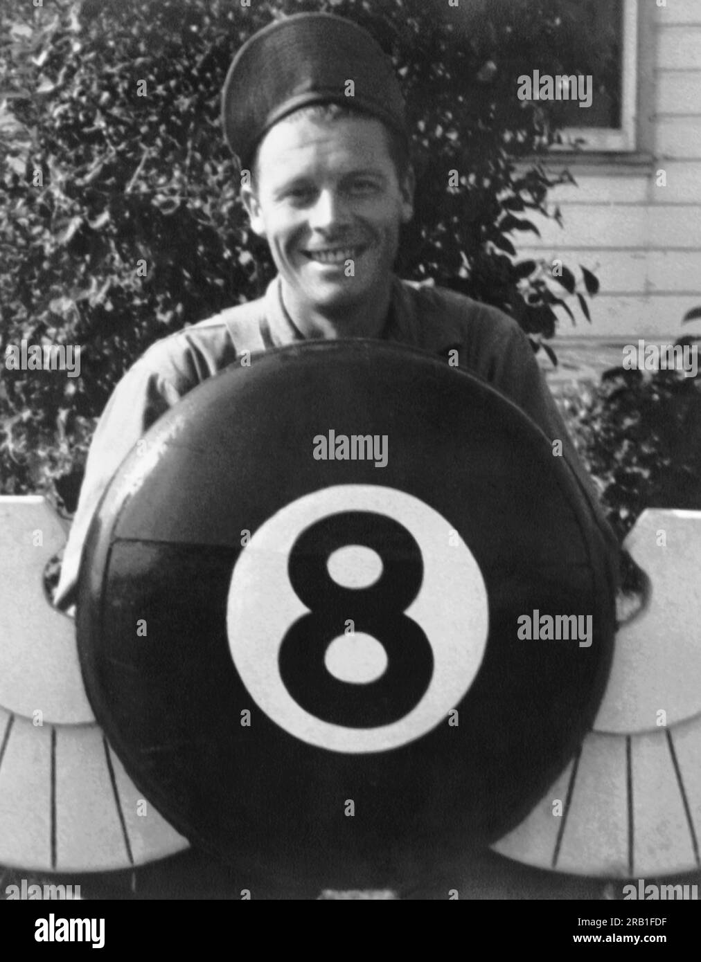 United States: c. 1940 A smiling man behind a very large eight ball ...