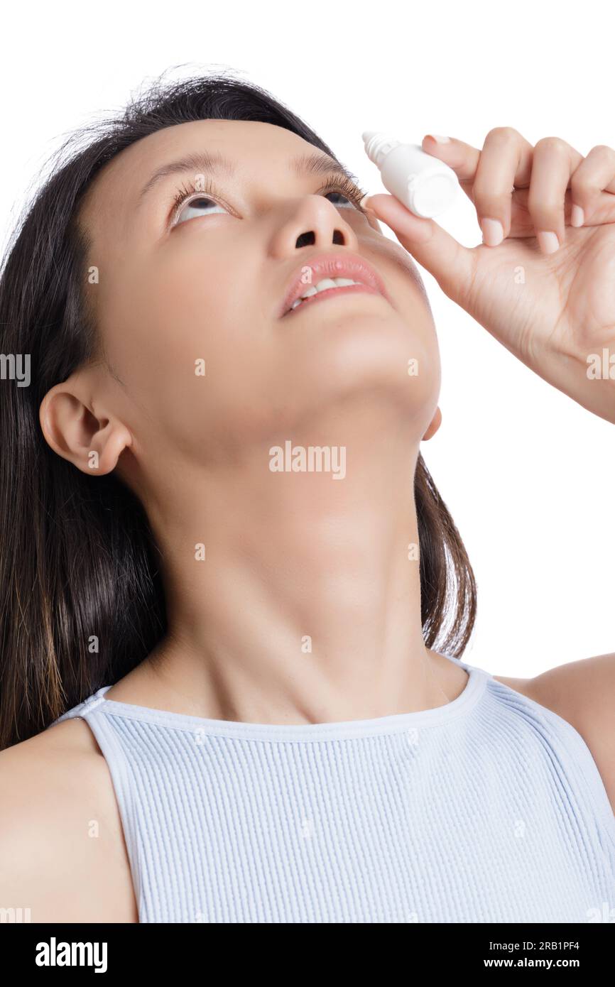 Beautiful Asian woman using eyedrops to relieve dry eyes isolated on a ...