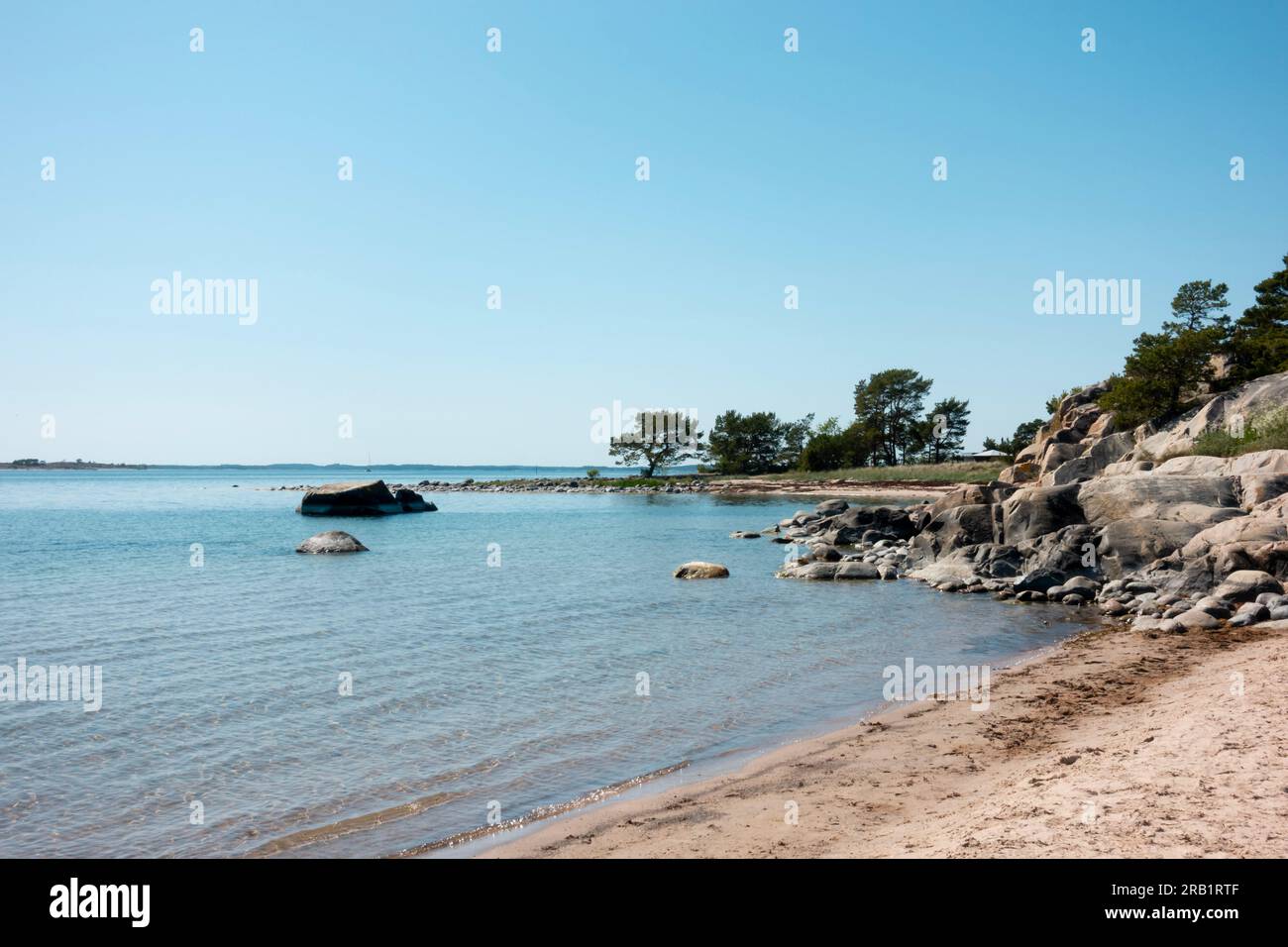 Beautiful coastal seaside landscape scene with sand beach meeting rocks ...
