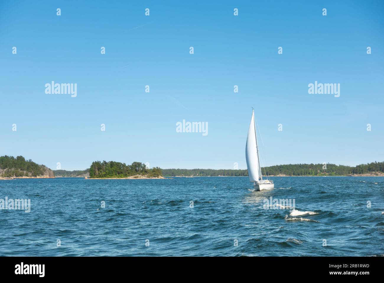 Summer recreational sailing activity with sailboat cruising between ...