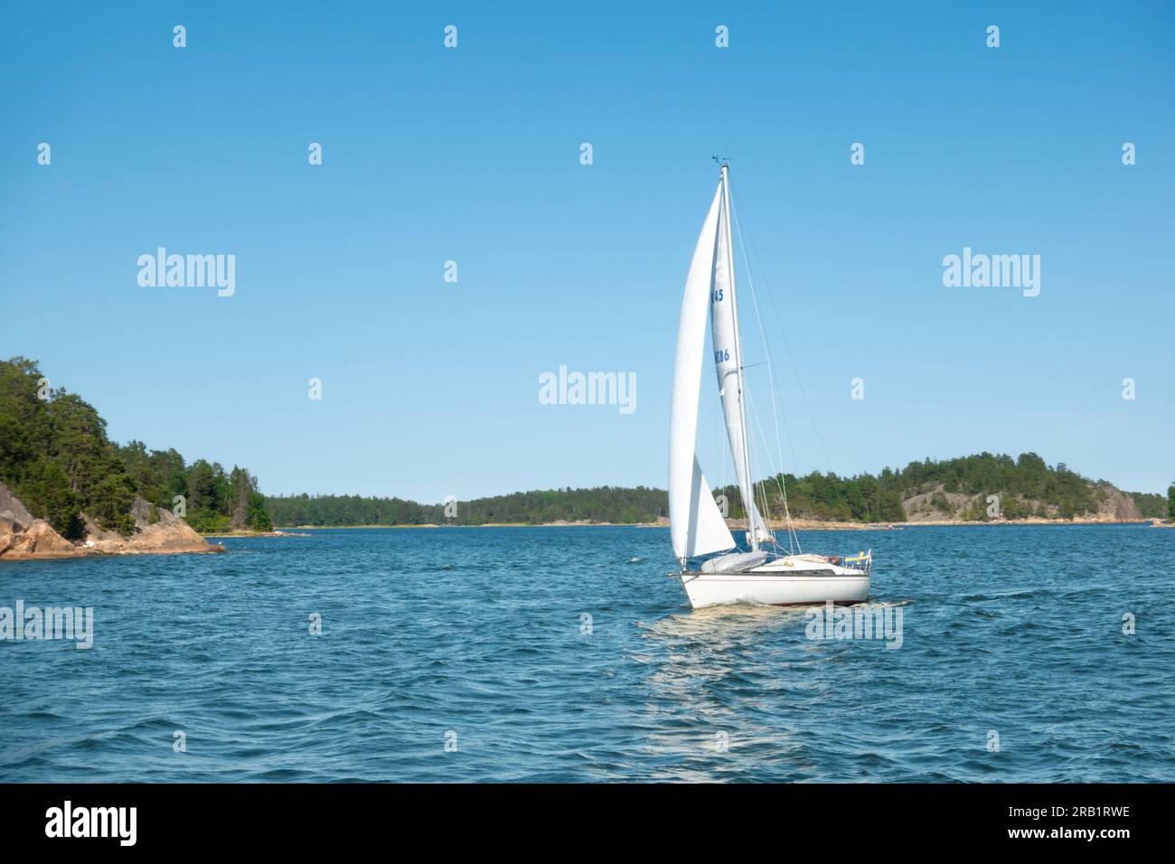 Summer recreational sailing activity with sailboat cruising between ...