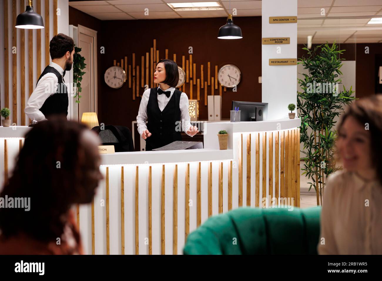 Front desk staff checking booking record at reception in lobby ...