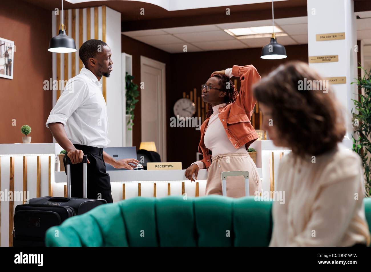 Couple ringing bell at reception desk and calling out receptionist to ...