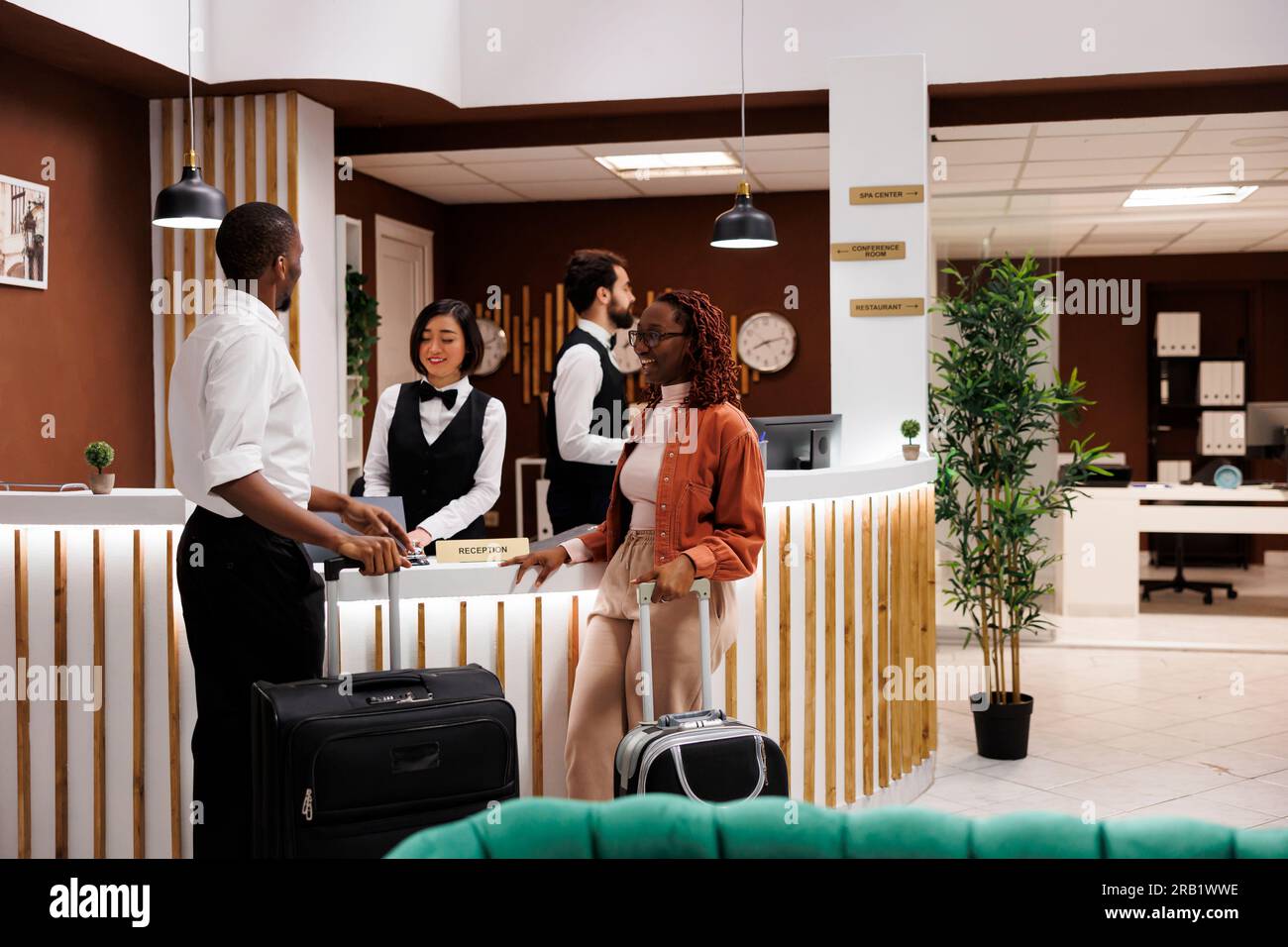 Couple arriving at hotel reception with luggage, talking to ...