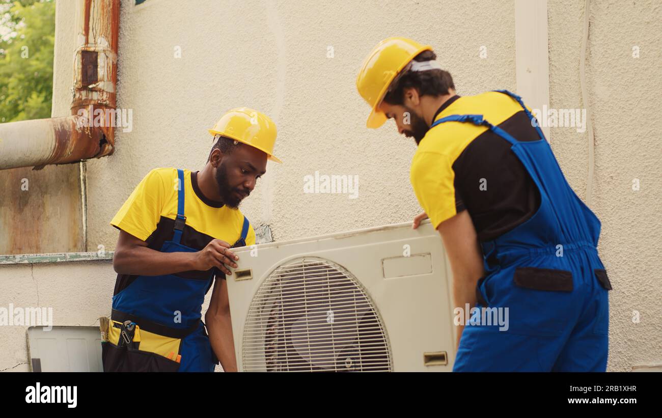 Teamworking diverse specialists starting work on damaged hvac system ...