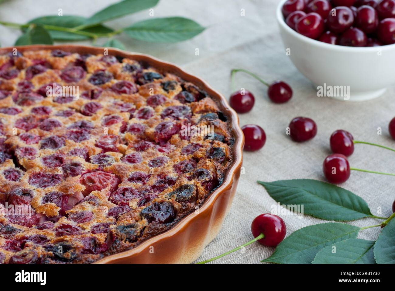 Delicious cherry clafoutis in round baking dish on light background ...