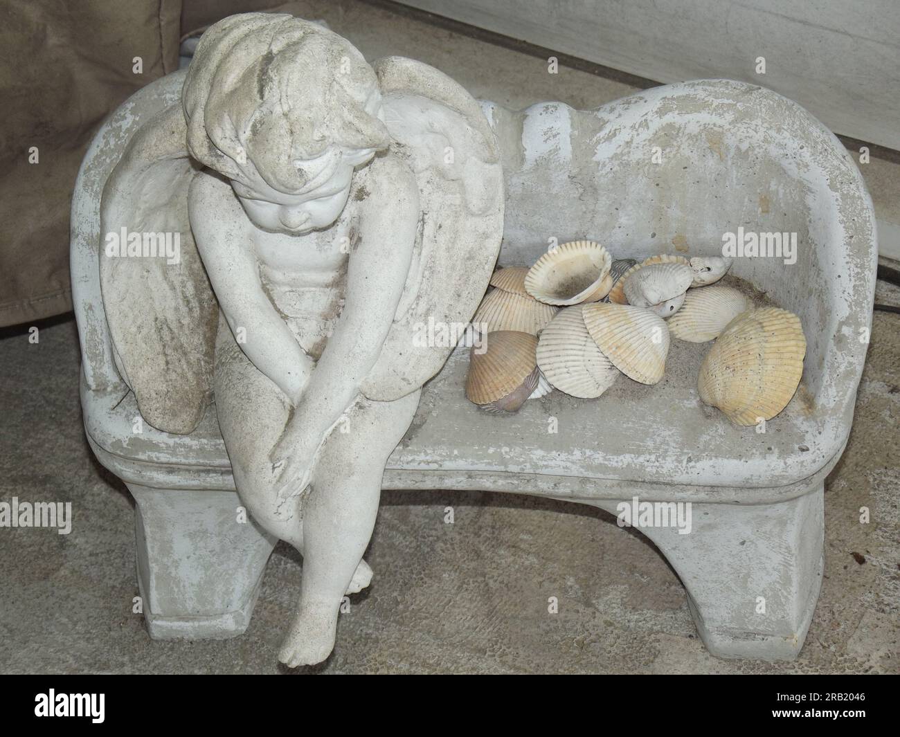 CONCRETE CHERUB SITTING ON A BENCH Stock Photo - Alamy