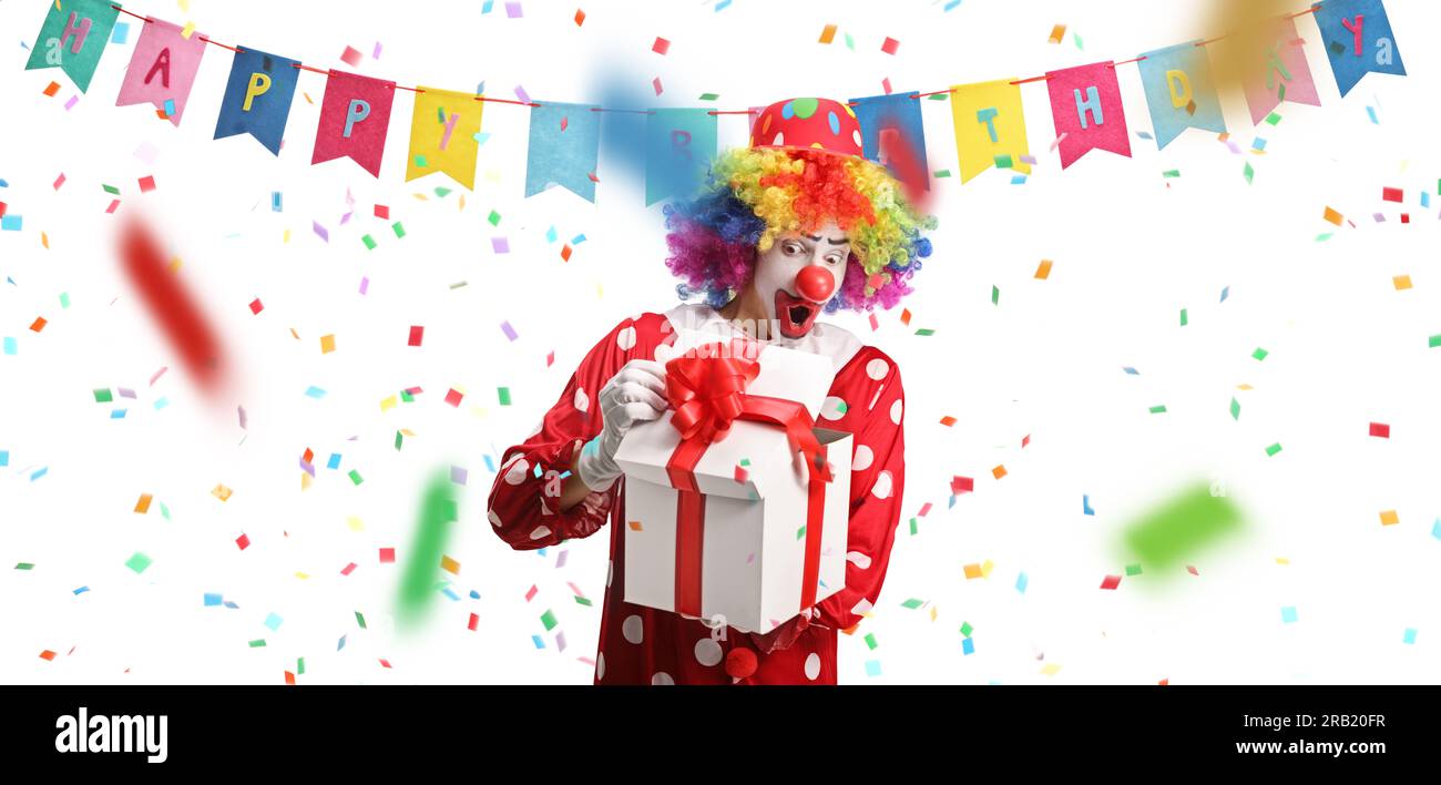 Clown opening a birthday present and confetti flying around isolated on ...