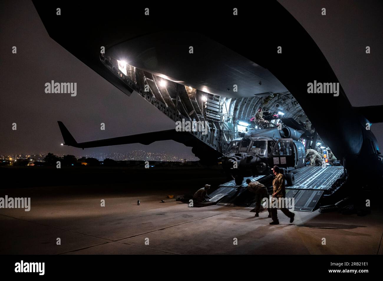 U.S. Army personnel unload a MH-60 Blackhawk from a C-17 Globemaster ...