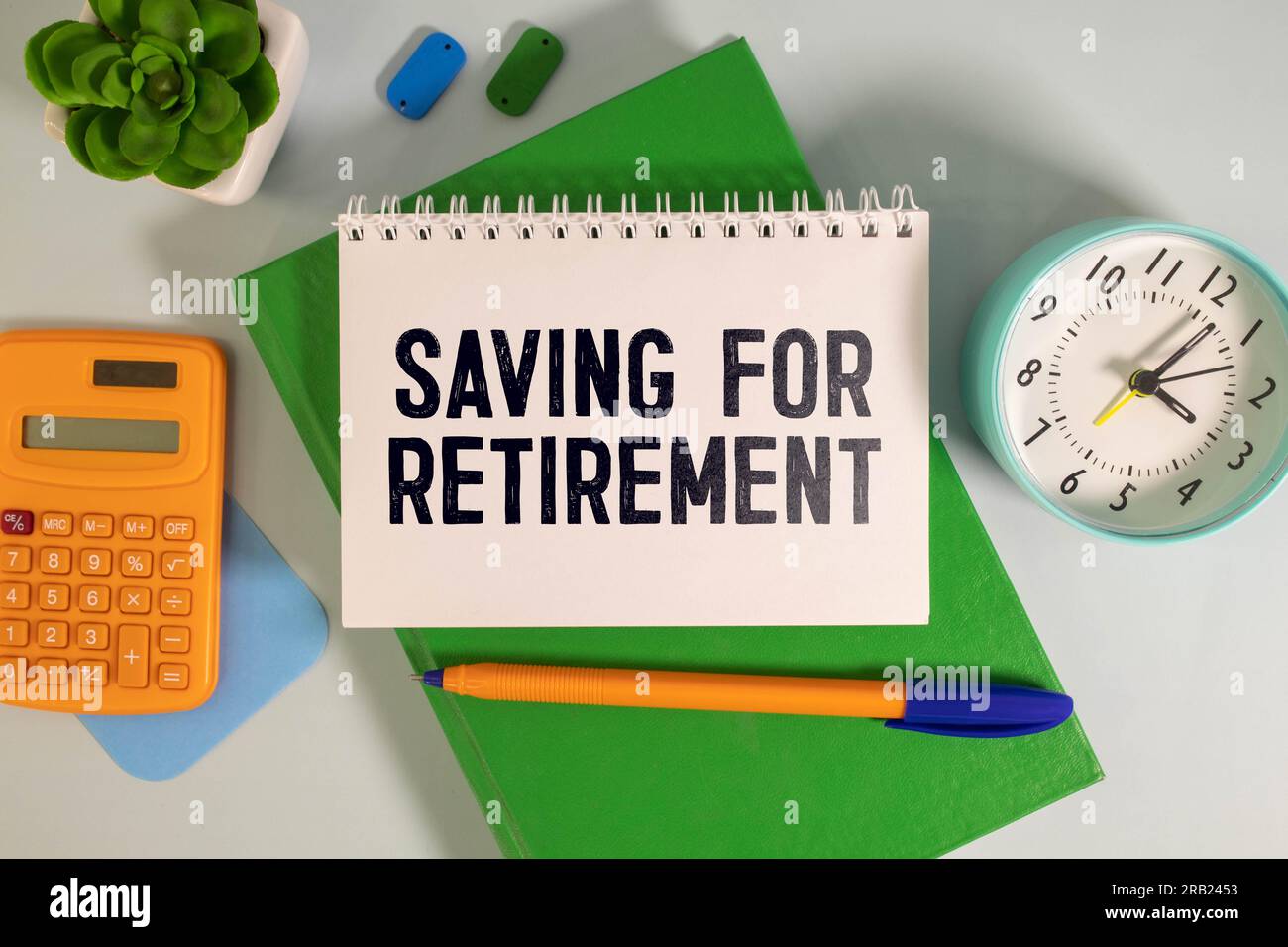 SAVING FOR RETIREMENT text on notebook with clipboard and calculator on ...