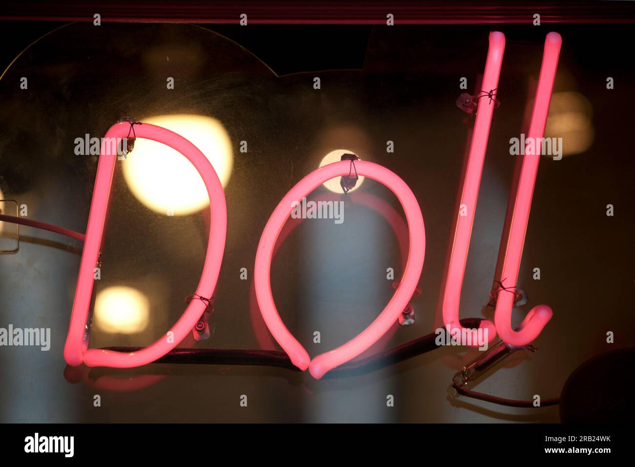 A pink neon light shaped into the word "Doll Stock Photo - Alamy