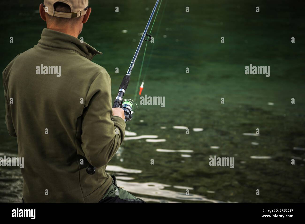 Back View of a Caucasian Man Fishing in a Lake Using Spinning Rod ...
