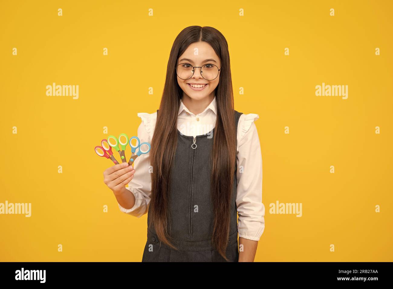 Teenage girl with scissors, isolated on yellow background. Child ...