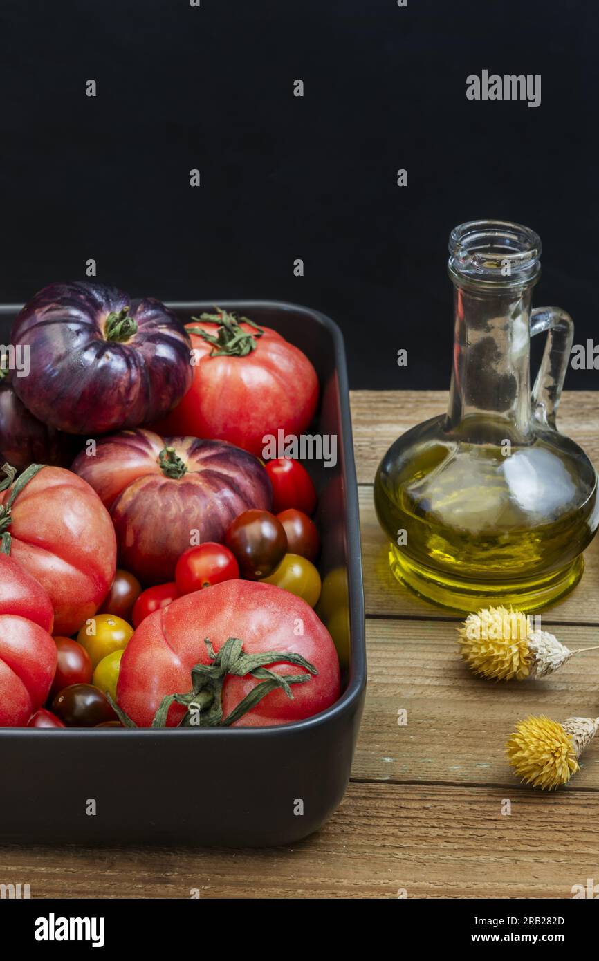 A still life with a tray full of tomatoes of various kinds and a ...