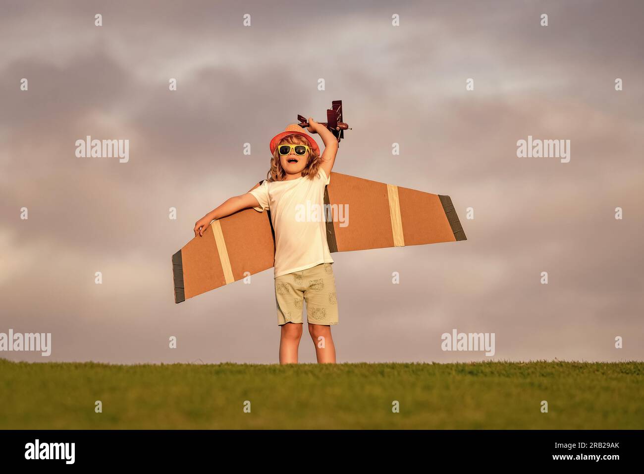 Kid pilot aviator with with paper wings dreams of traveling in summer ...