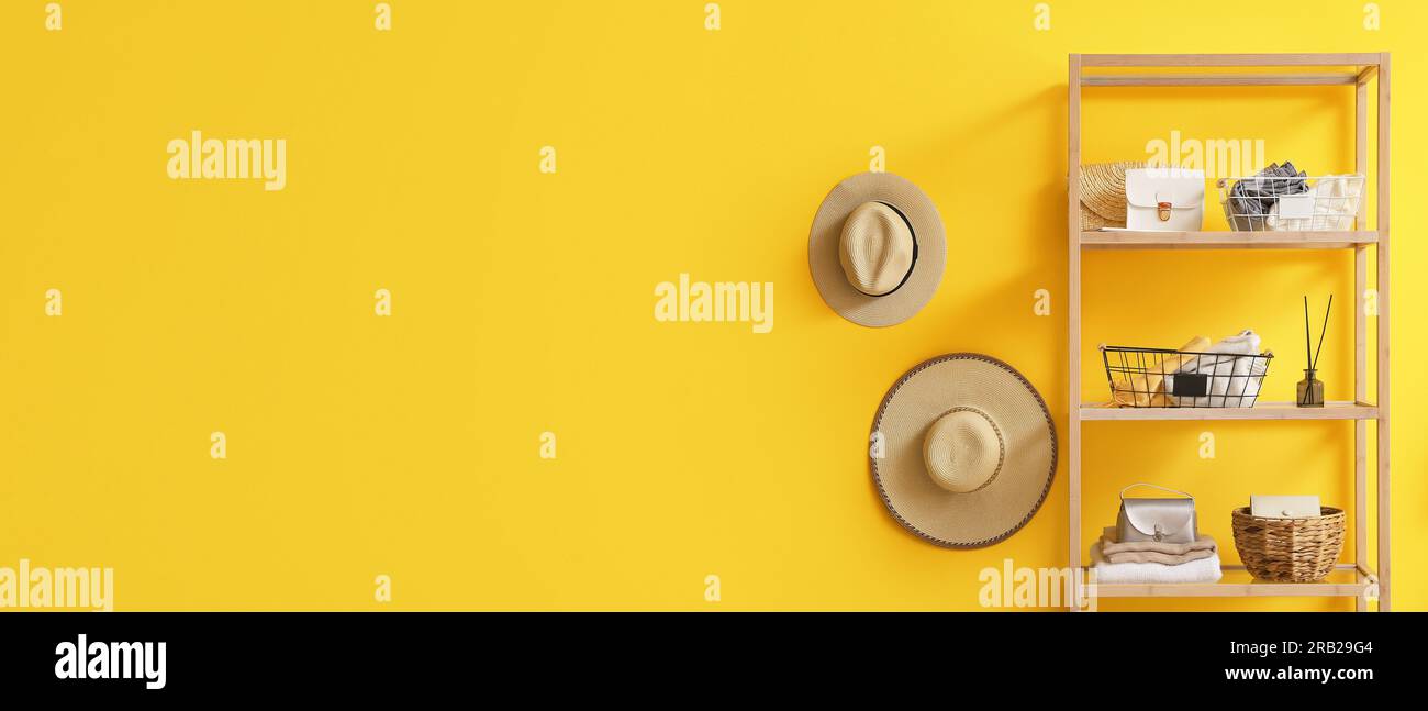 Wooden shelving unit with female clothes and accessories near yellow ...