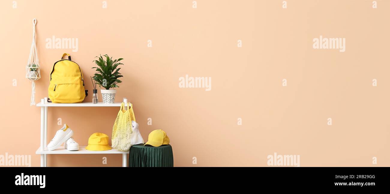 Shelving unit with modern clothes and accessories near color wall ...