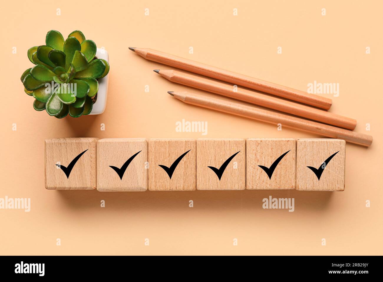 Wooden cubes with check marks, plant and pencils on beige background ...