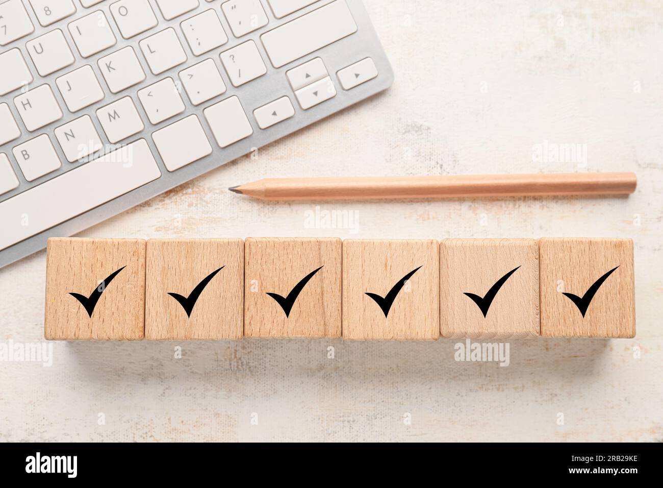 Wooden cubes with check marks, pencil and computer keyboard on light ...