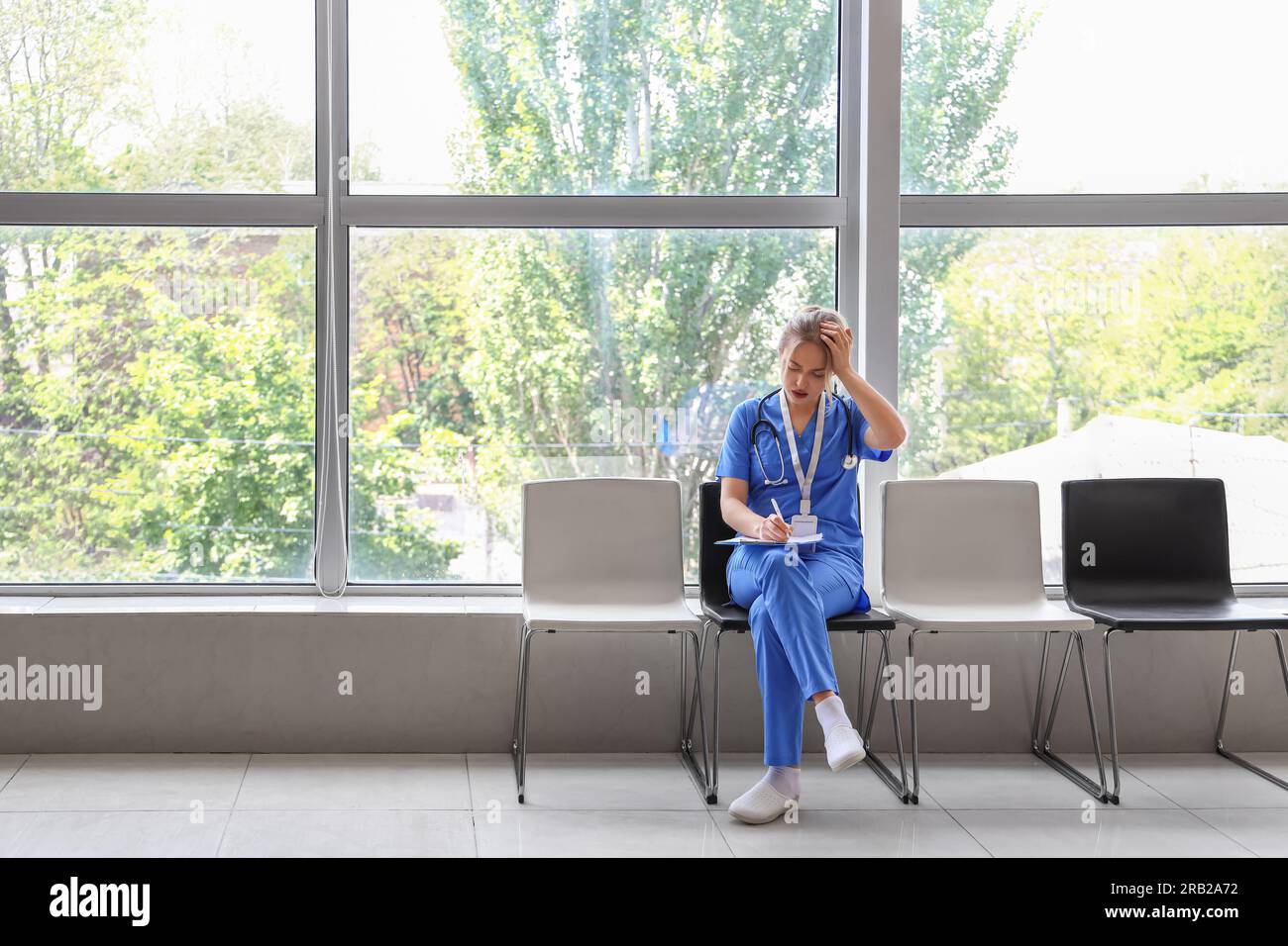 Stressed female medical intern writing in clipboard at hospital Stock ...