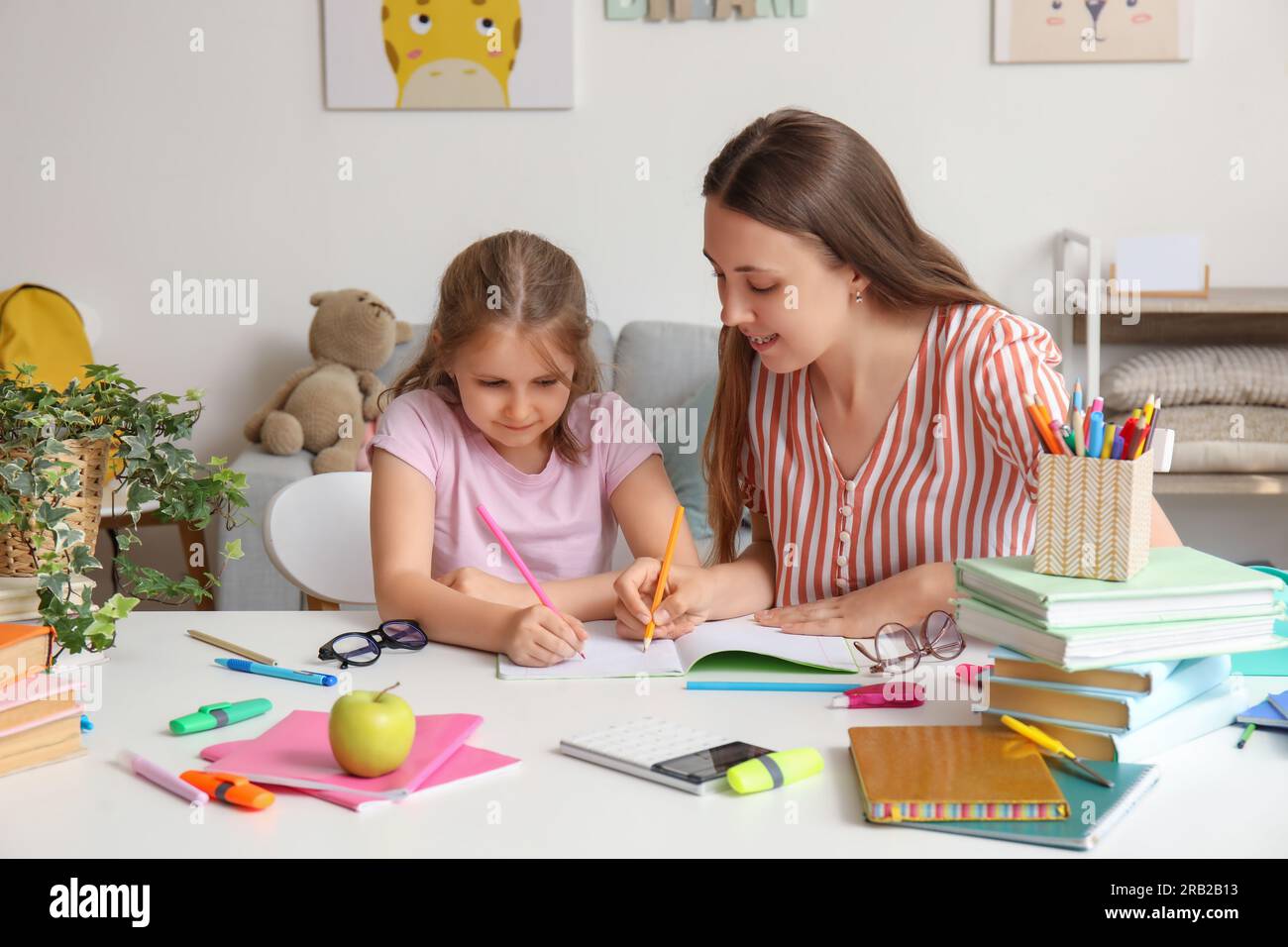 Cute little girl doing lessons with her mother at home Stock Photo - Alamy