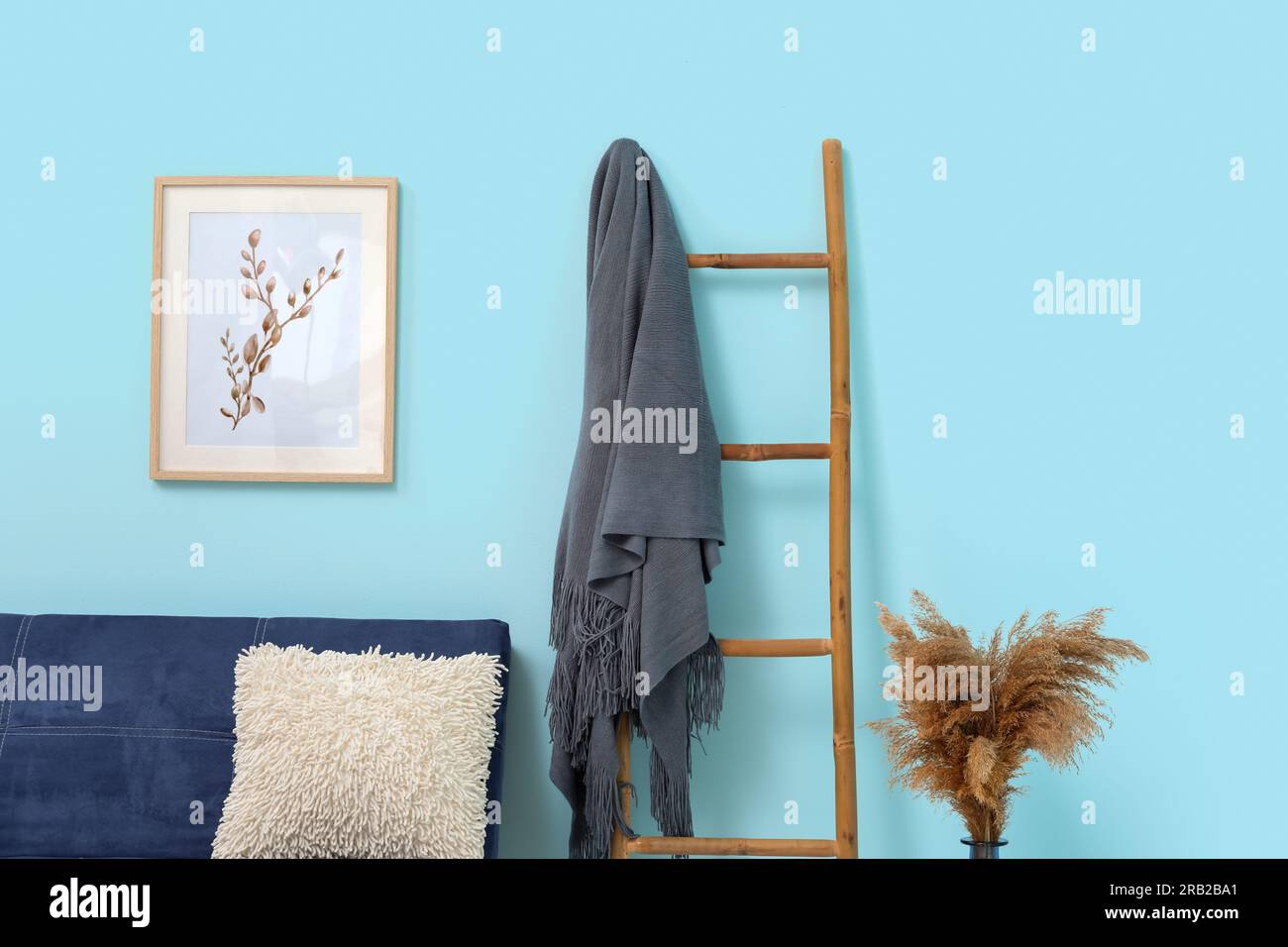 Wooden ladder with blanket, sofa, pampas grass and picture hanging on ...