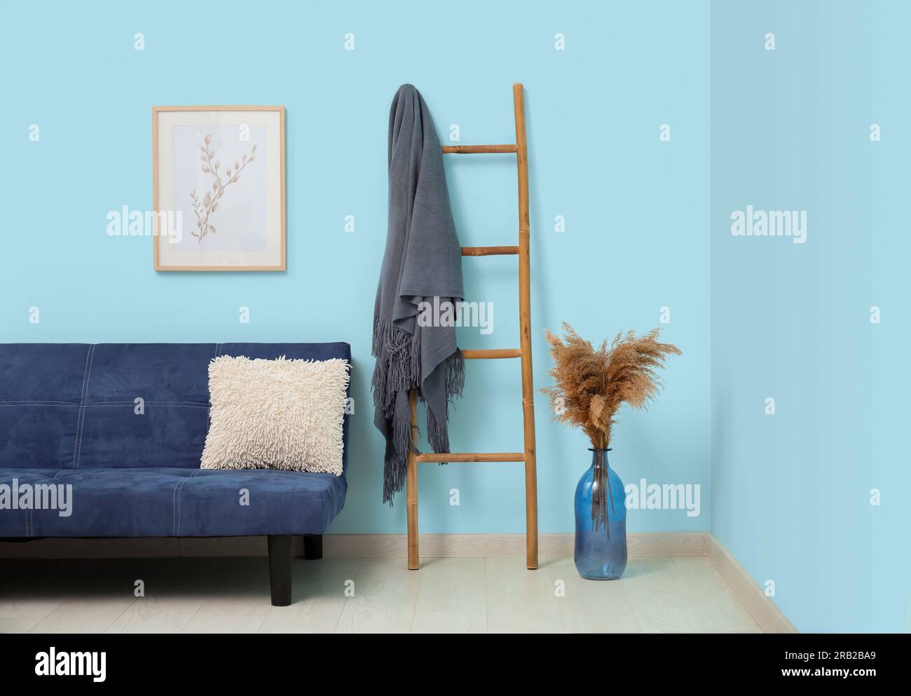 Wooden ladder with blanket, sofa, pampas grass and picture hanging on ...