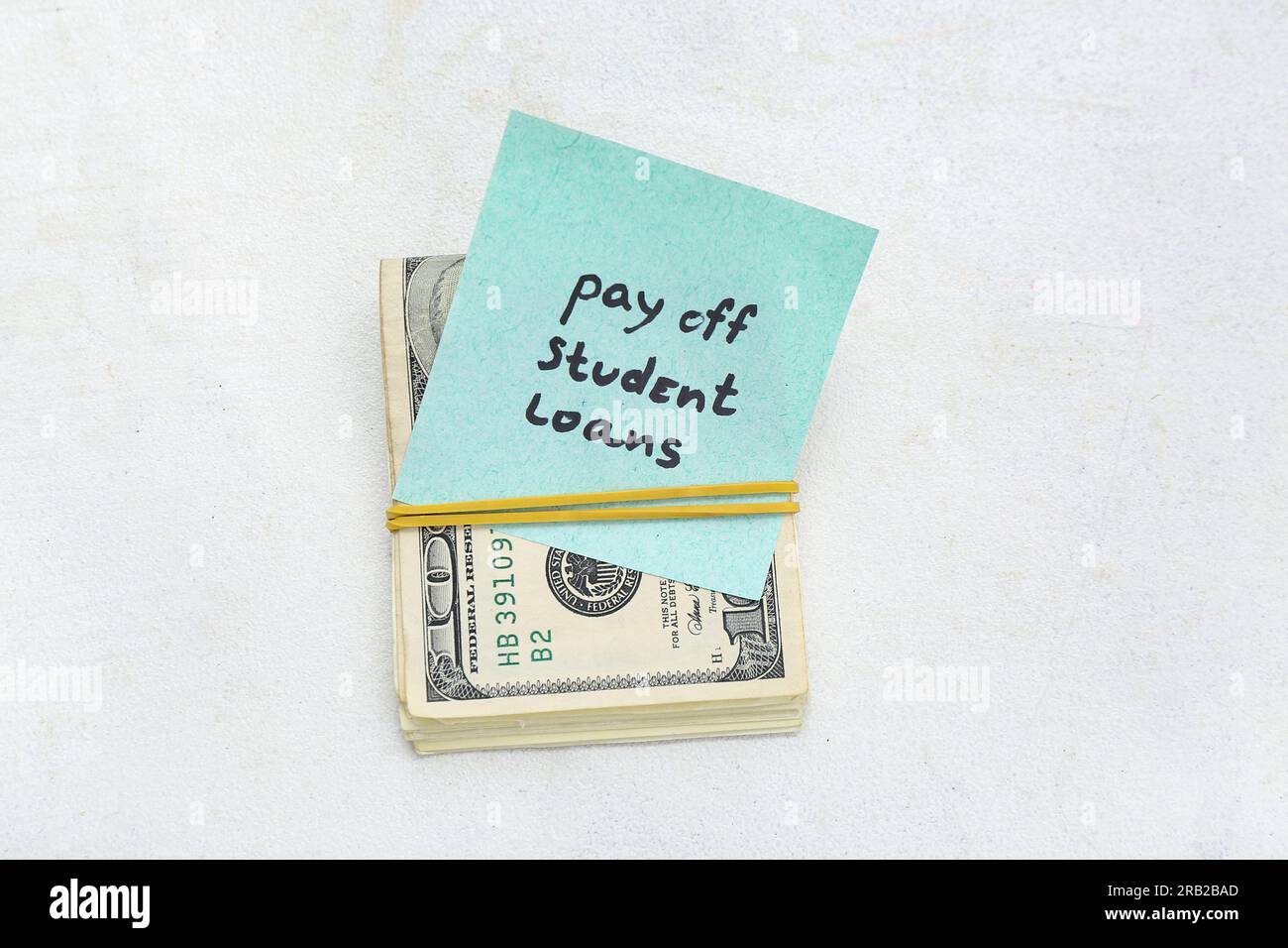 Dollar banknotes and sticky note with text PAY OFF STUDENT LOANS on ...