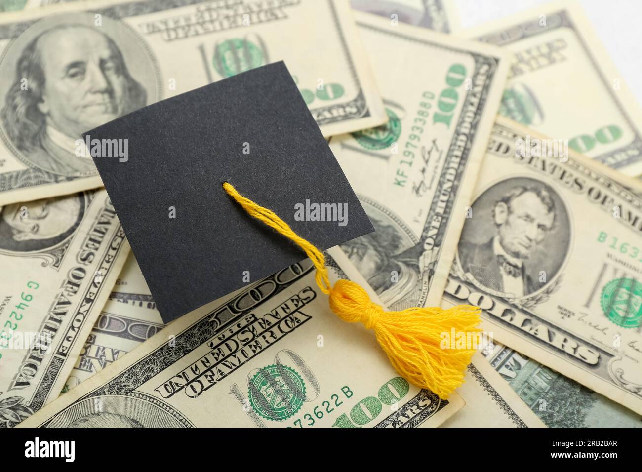 Graduation hat on pile of dollar banknotes. Student loan concept Stock ...