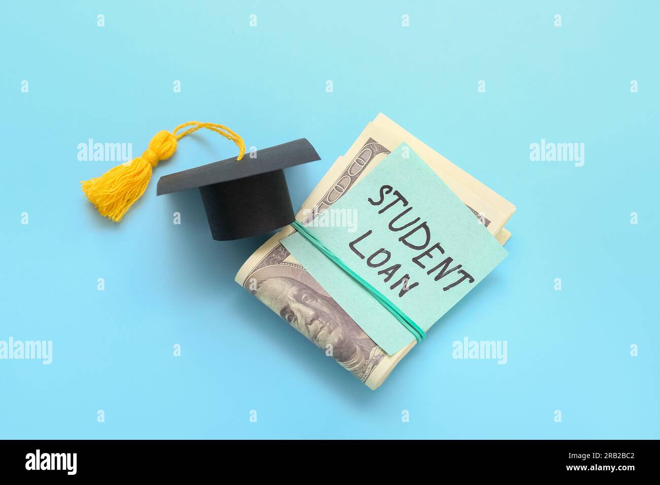 Dollar banknotes, graduation cap and sticky note with text STUDENT LOAN ...