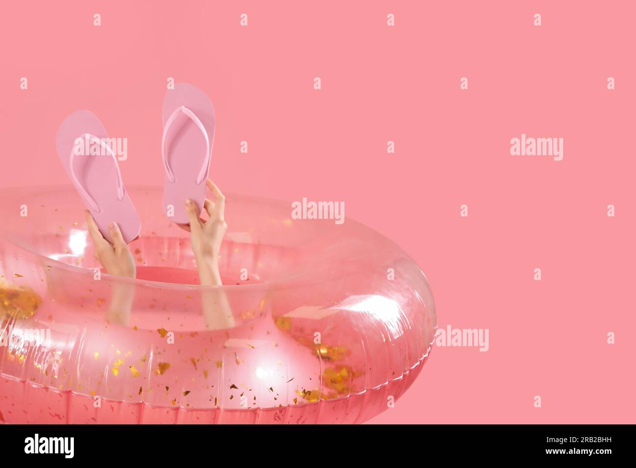 Hands with flip-flops and inflatable ring on pink background Stock ...