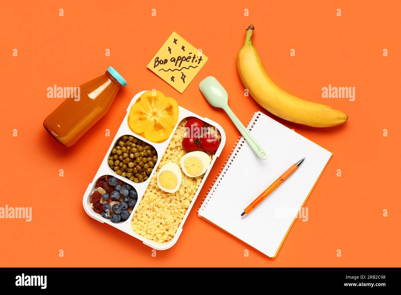 Stationery, tasty food in lunchbox and sticky note with text BON ...