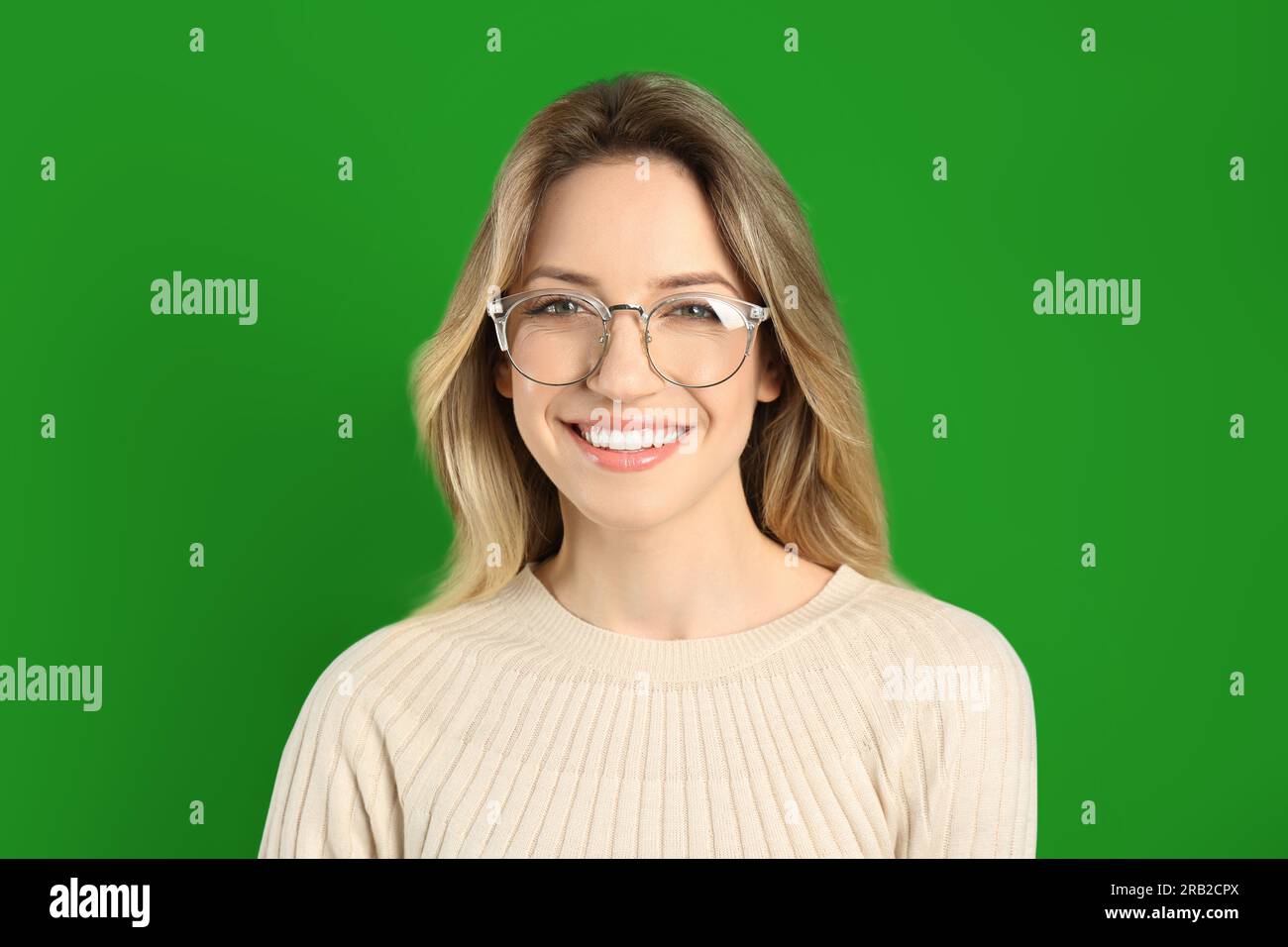 Chroma key compositing. Happy young woman smiling against green screen ...