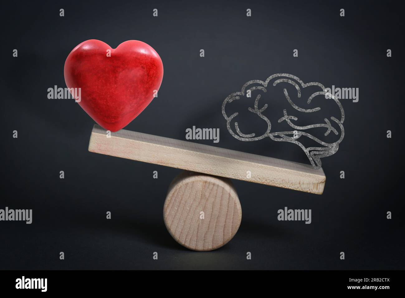Choosing between logic and emotions. Miniature wooden seesaw with heart ...