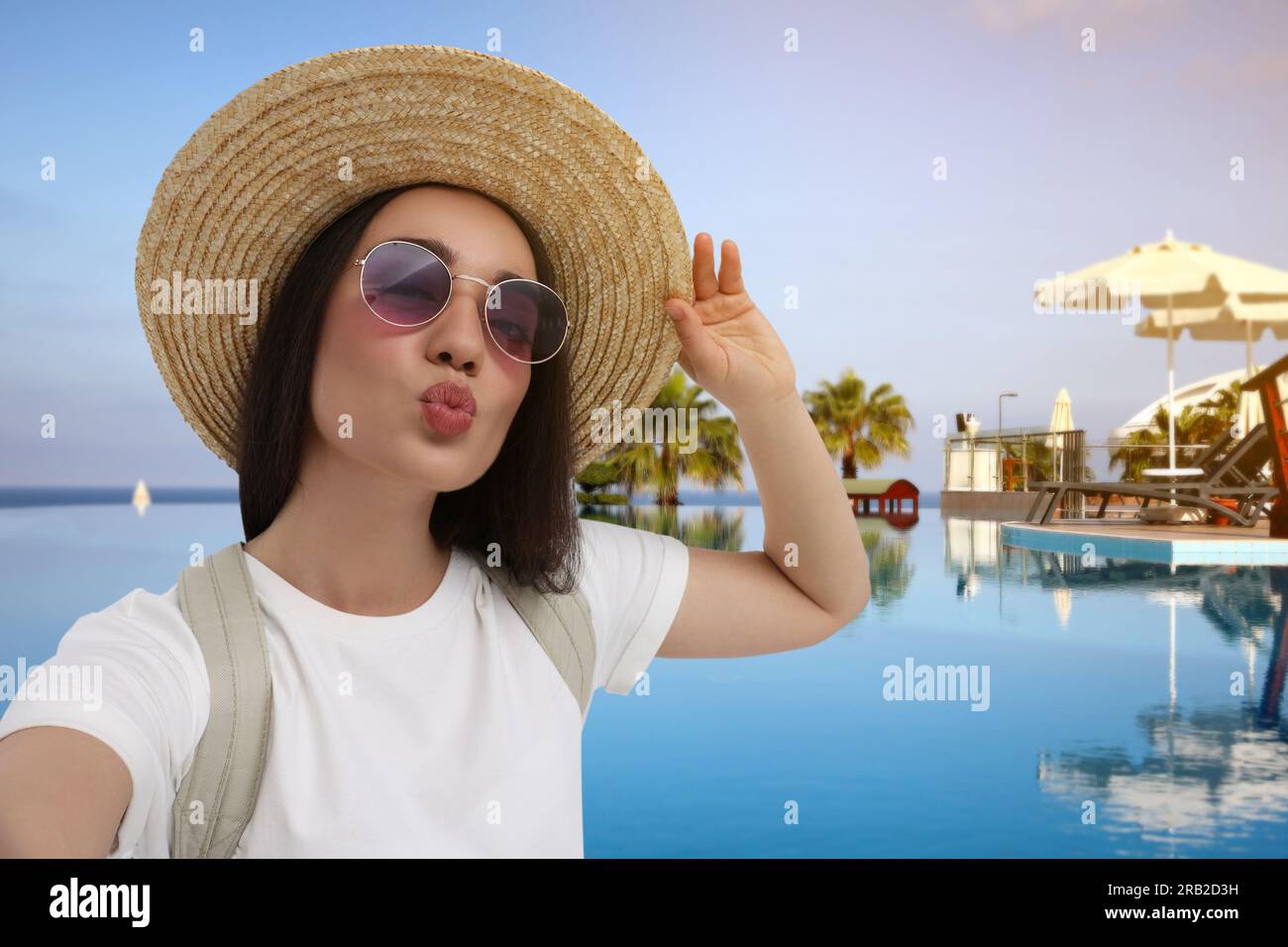 Smiling Young Woman In Sunglasses And Straw Hat Taking Selfie At Resort