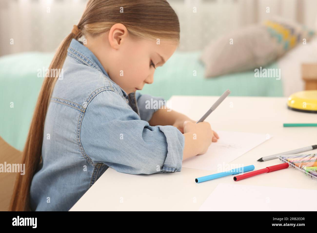 Cute little girl drawing with marker at desk in room. Home workplace ...