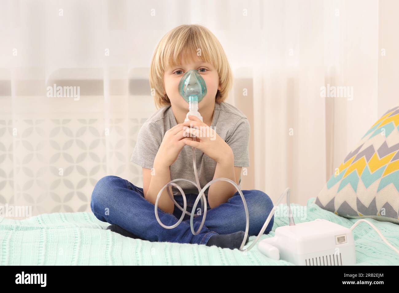 Sick little boy using nebulizer for inhalation on bed at home Stock ...
