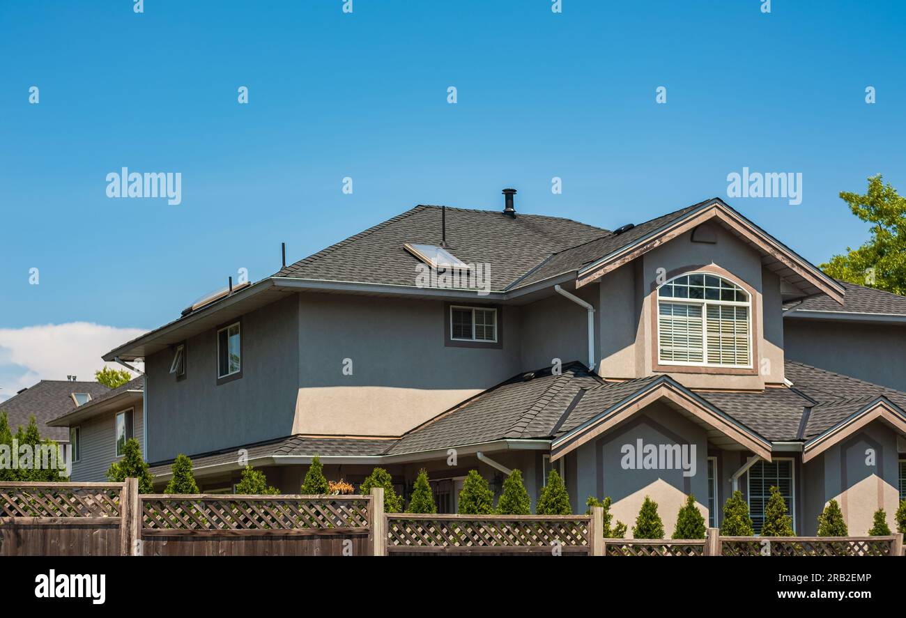 Houses with shingle roof against blue sky. Edge of roof shingles on top ...
