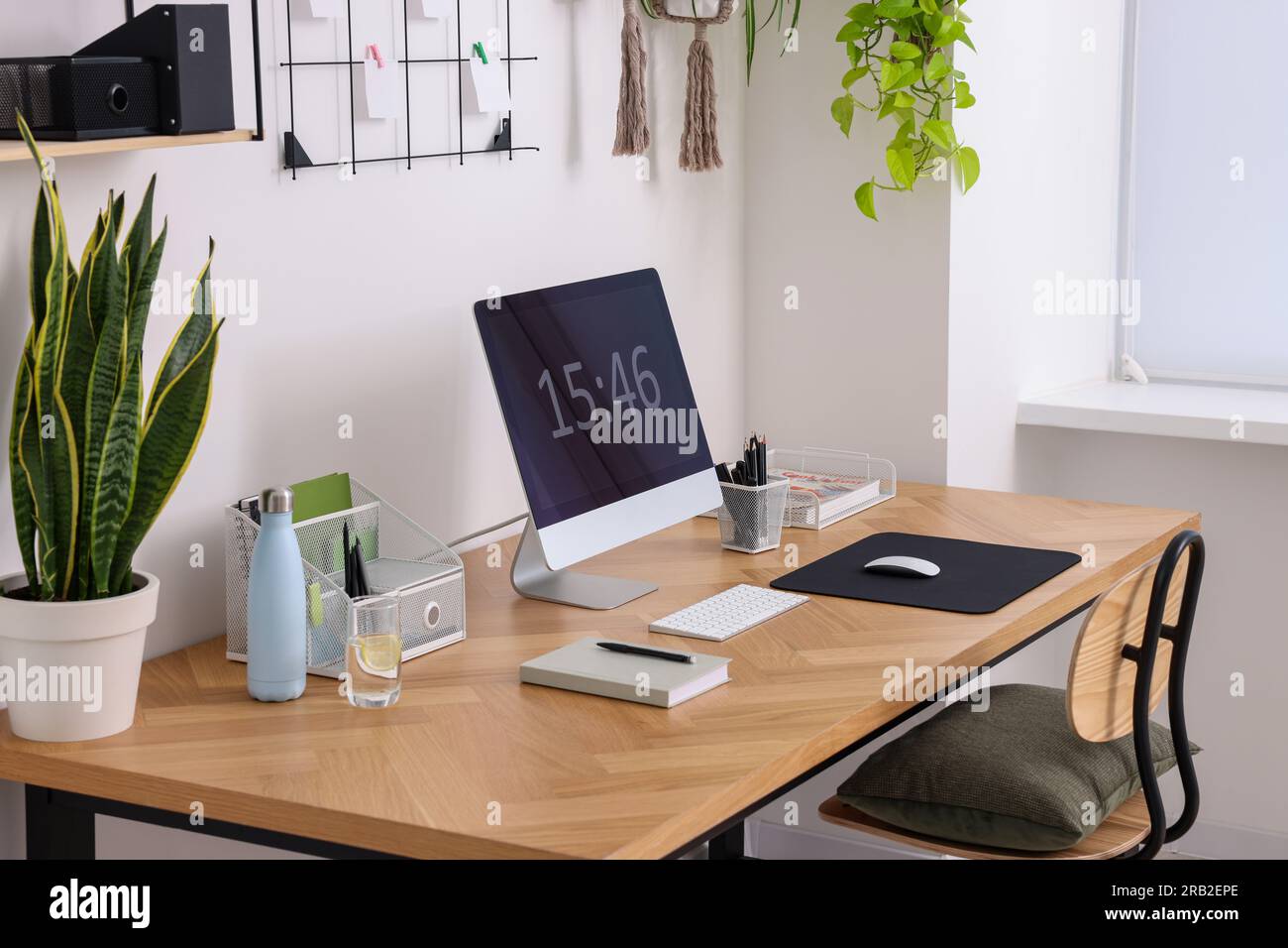 Cozy workplace with computer, modern furniture and houseplants at home ...