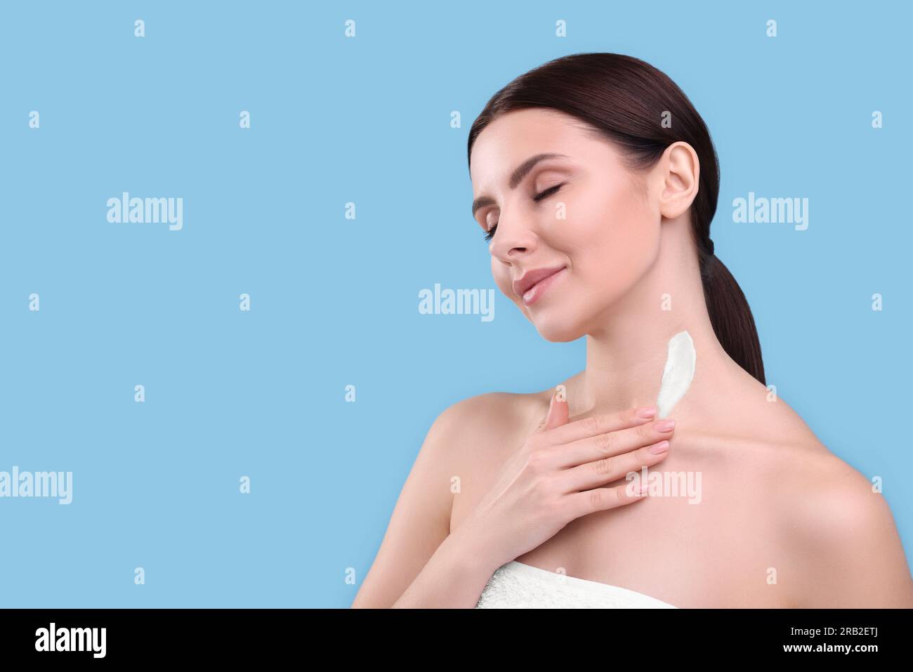 Beautiful woman with smear of body cream on her neck against light blue ...