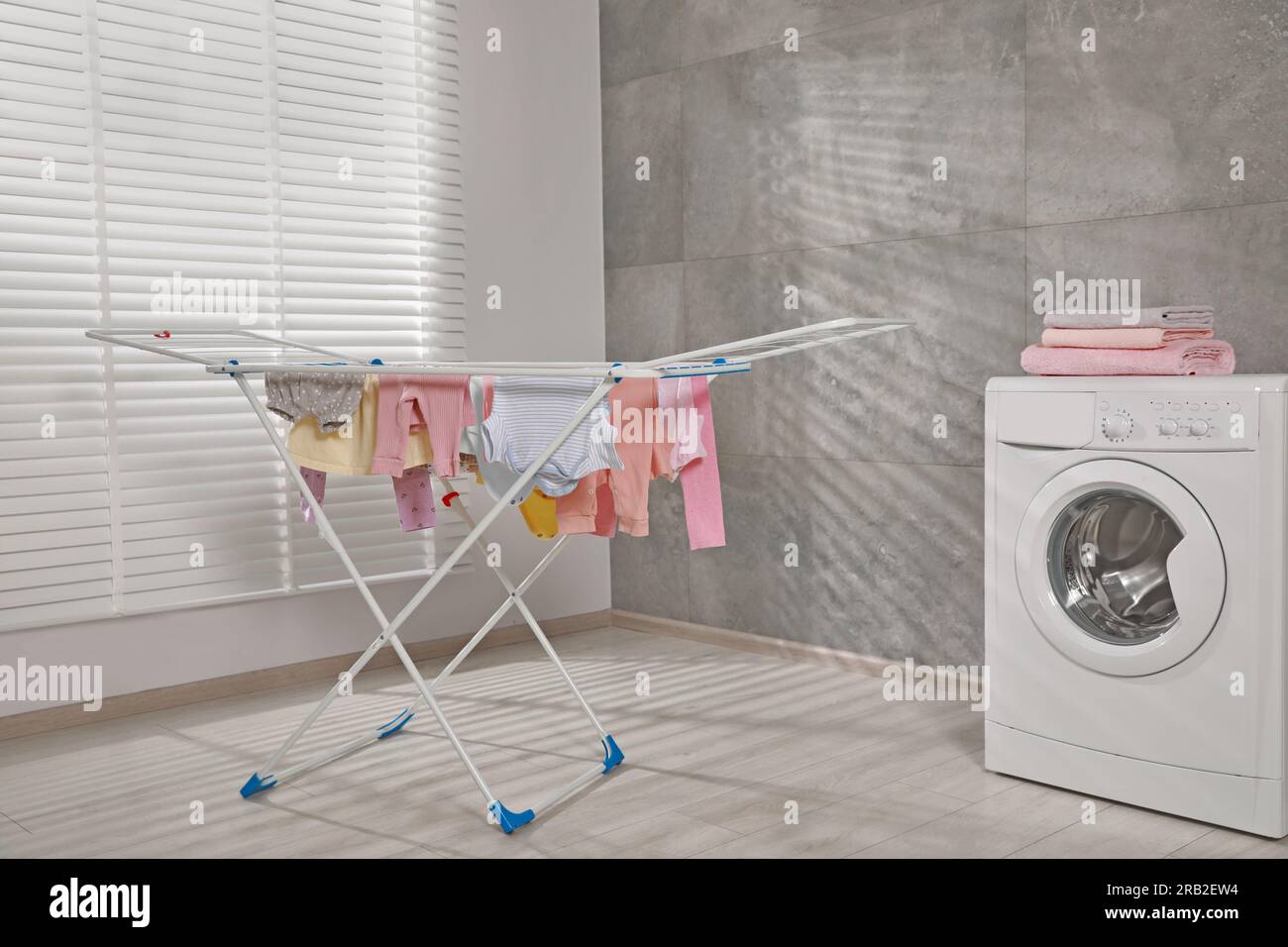 Clean laundry hanging on drying rack indoors Stock Photo - Alamy