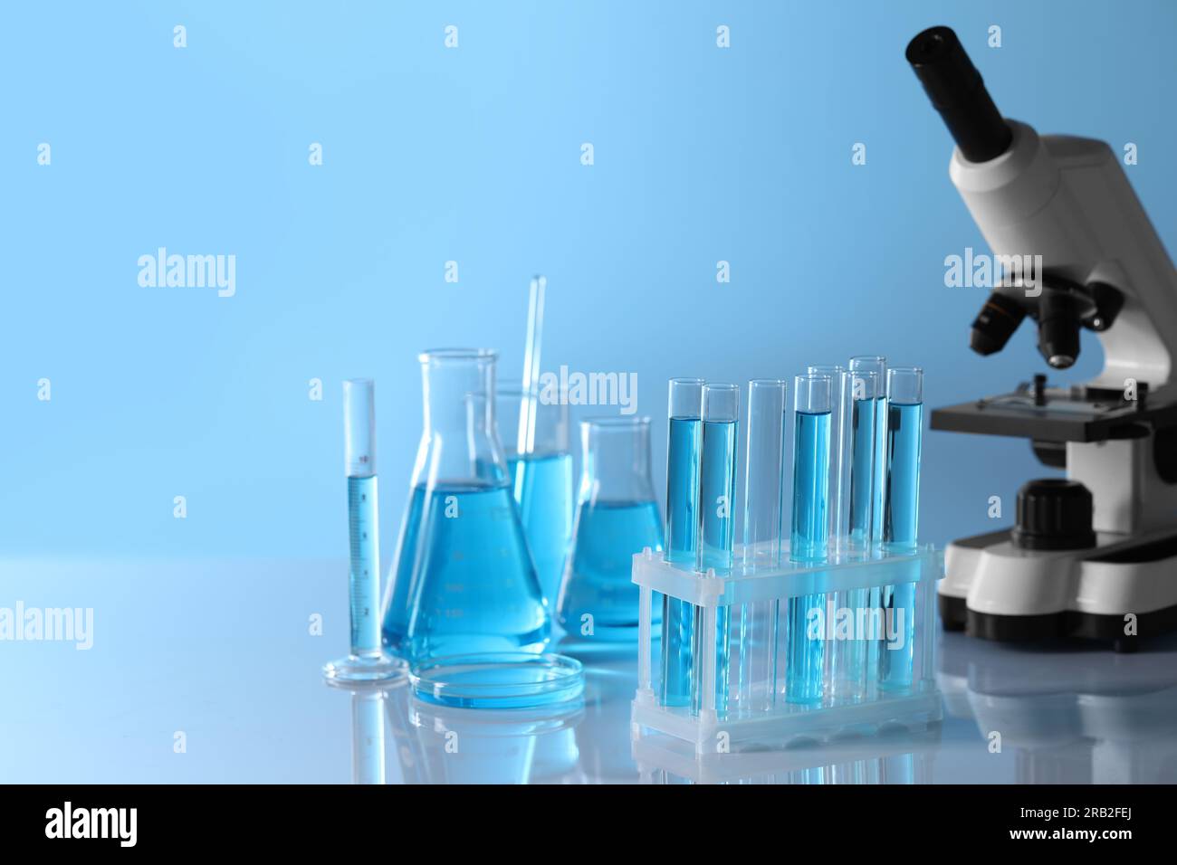 Microscope near different laboratory glassware and test tubes with ...