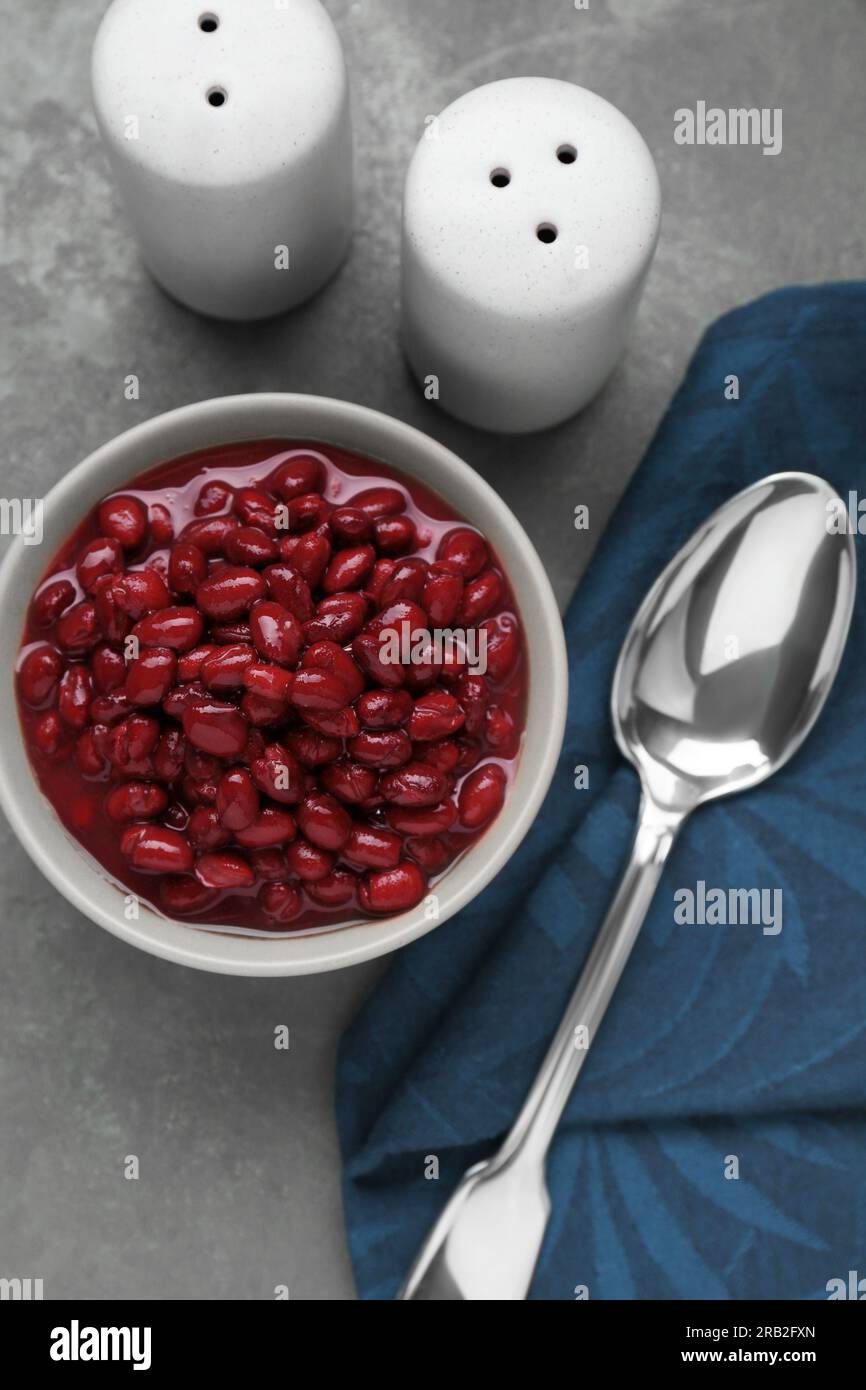 Bowl of canned kidney beans, spoon and shakers on grey table, flat lay ...