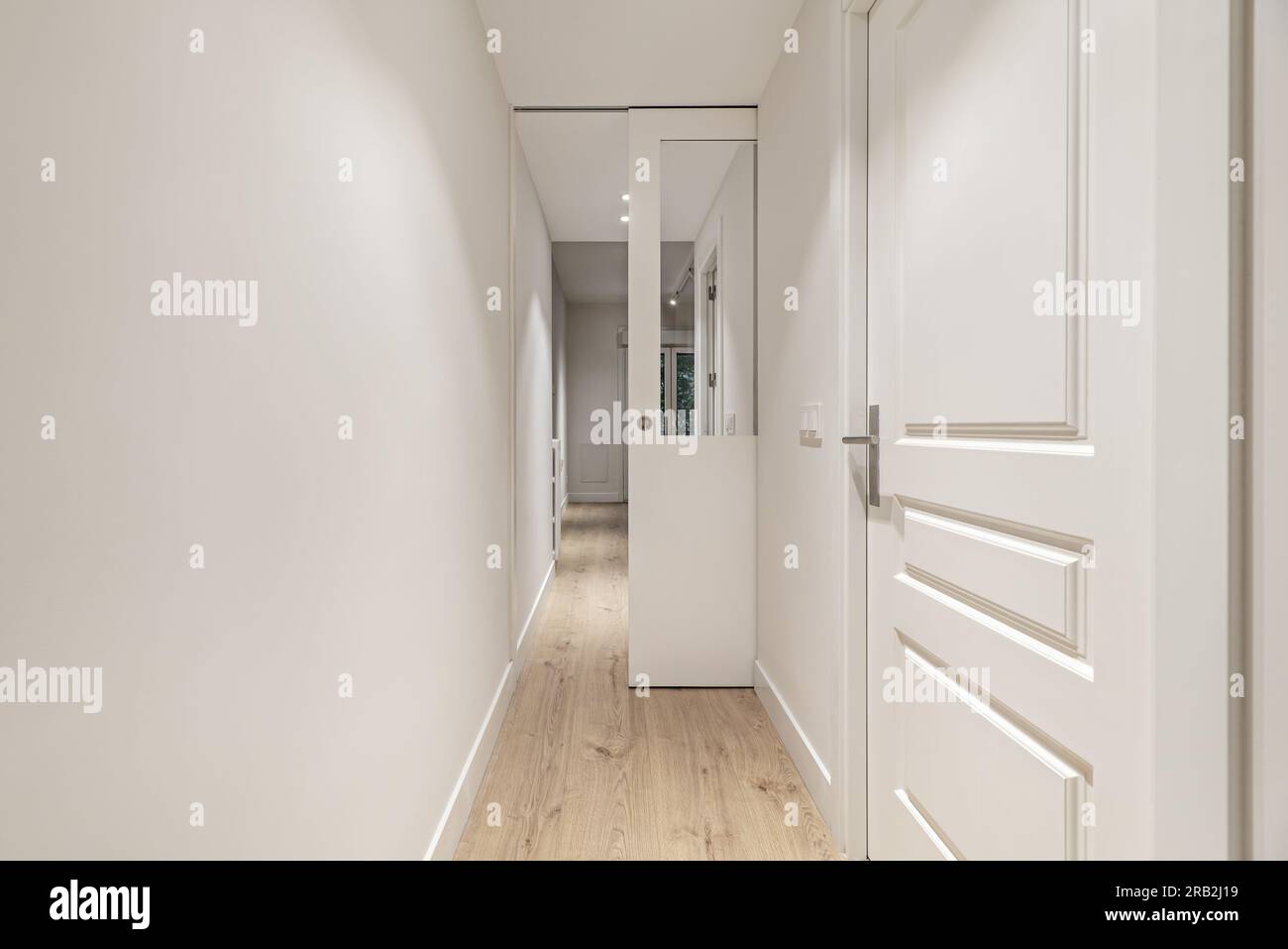 Corridor of a house with plain white painted walls, white lacquered ...