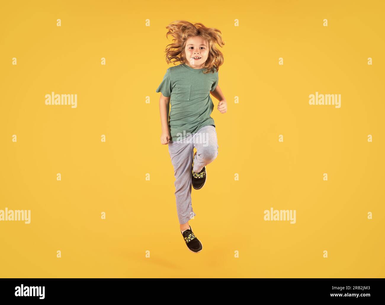 Energetic kid boy jumping and raising hands up on isolated studio ...